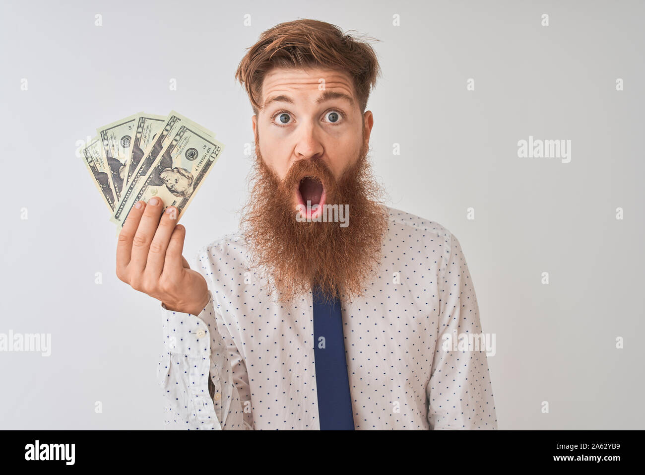 Young redhead irish businessman holding dollars standing over isolated ...