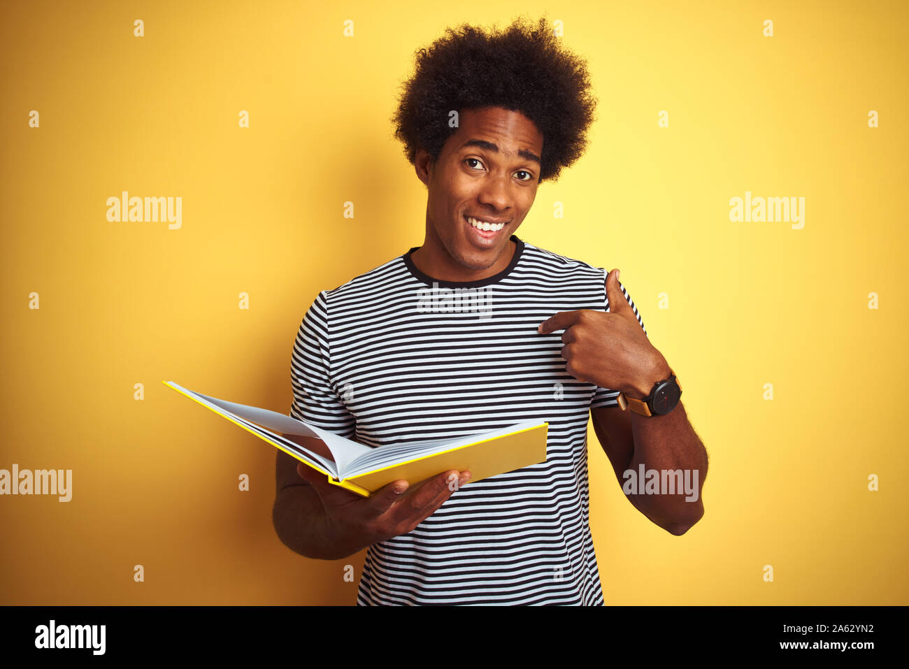 Afro american student man reading book standing over isolated yellow ...
