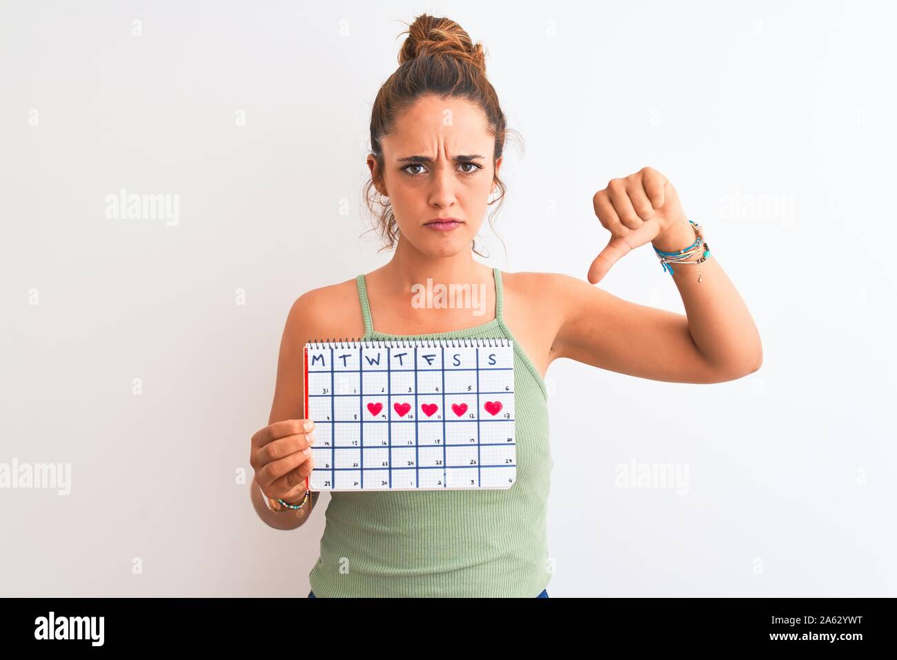 Young redhead woman holding menstruation calendar over isolated ...