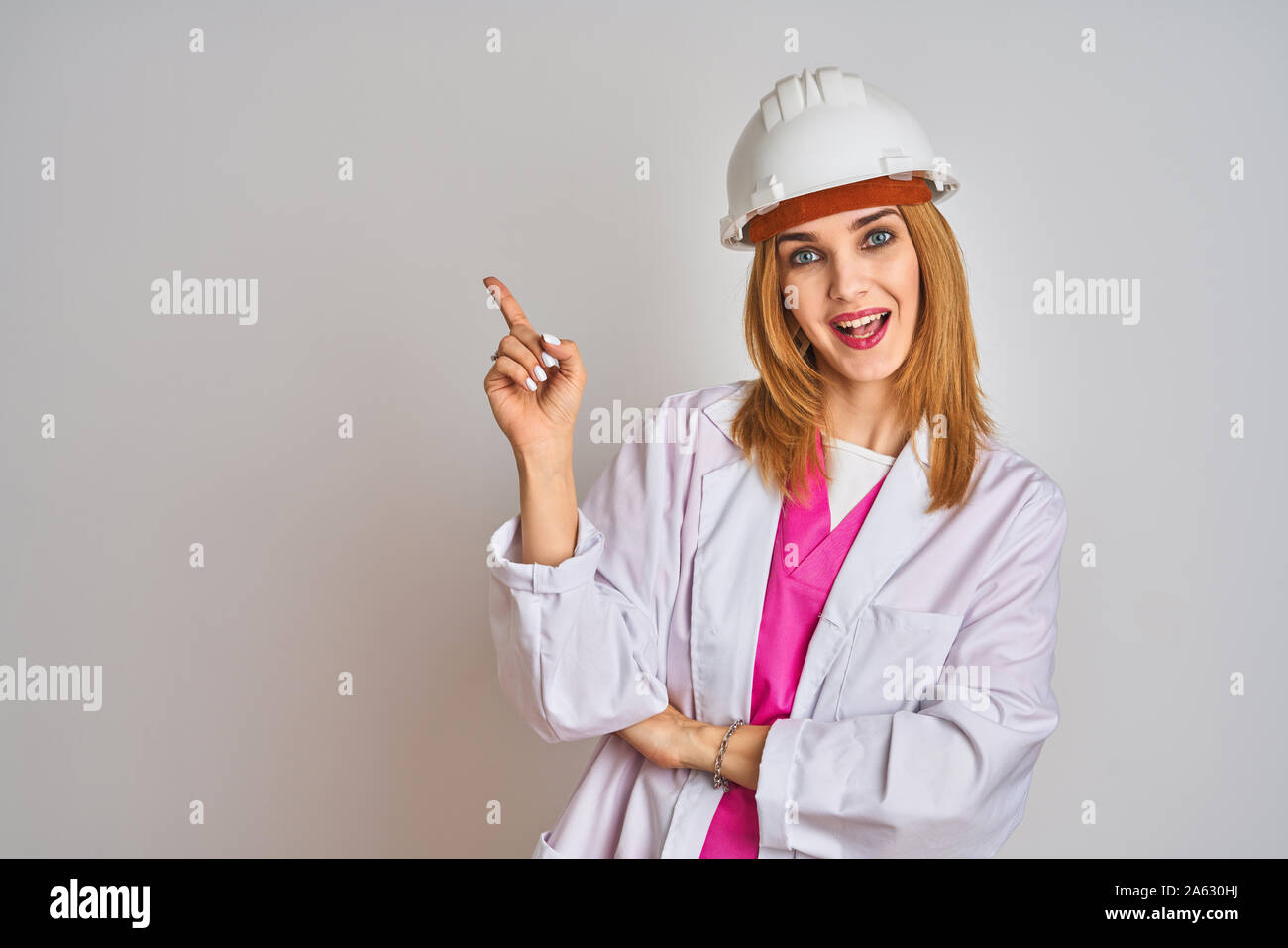 Redhead caucasian woman engineer wearing safety helmet over isolated ...