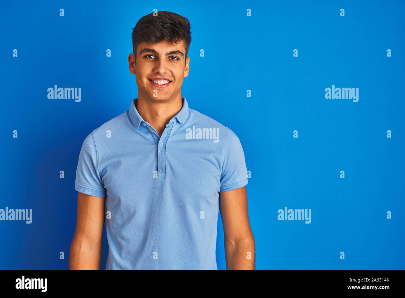 Young indian man wearing casual polo standing over isolated blue ...