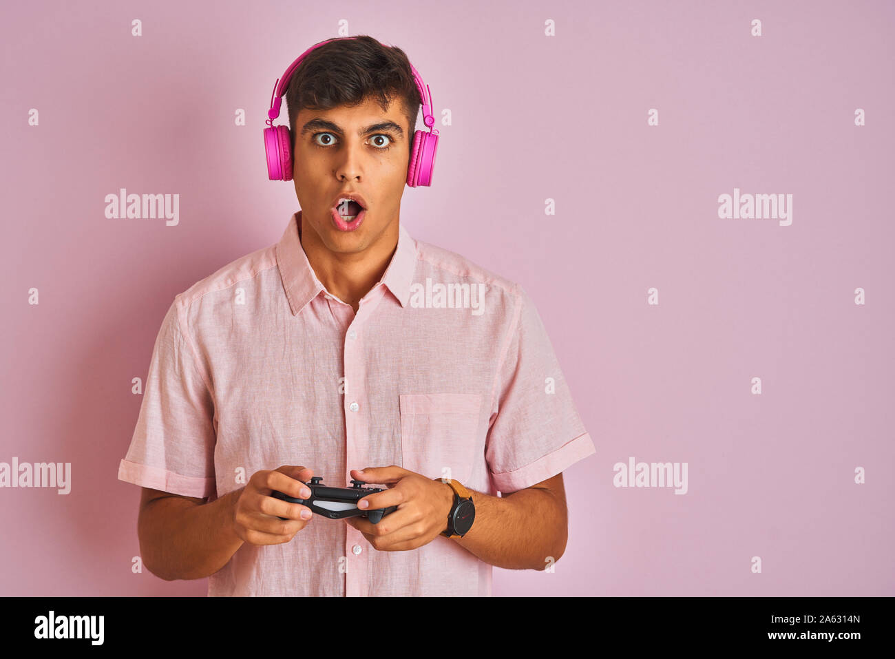 Indian gamer man playing video game using headphones over isolated pink ...
