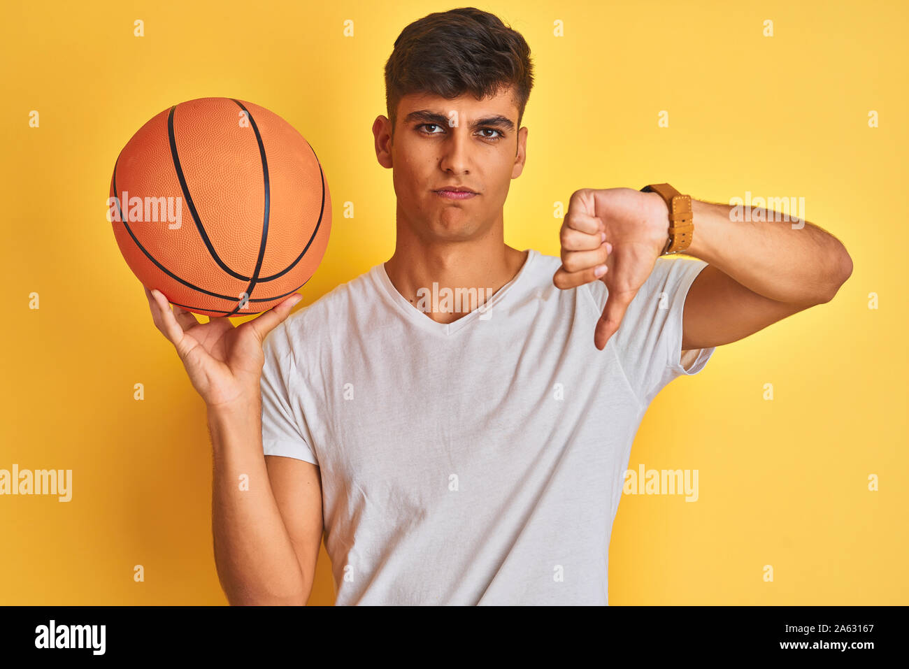 Young indian sportsman holding basketball ball standing over isolated ...