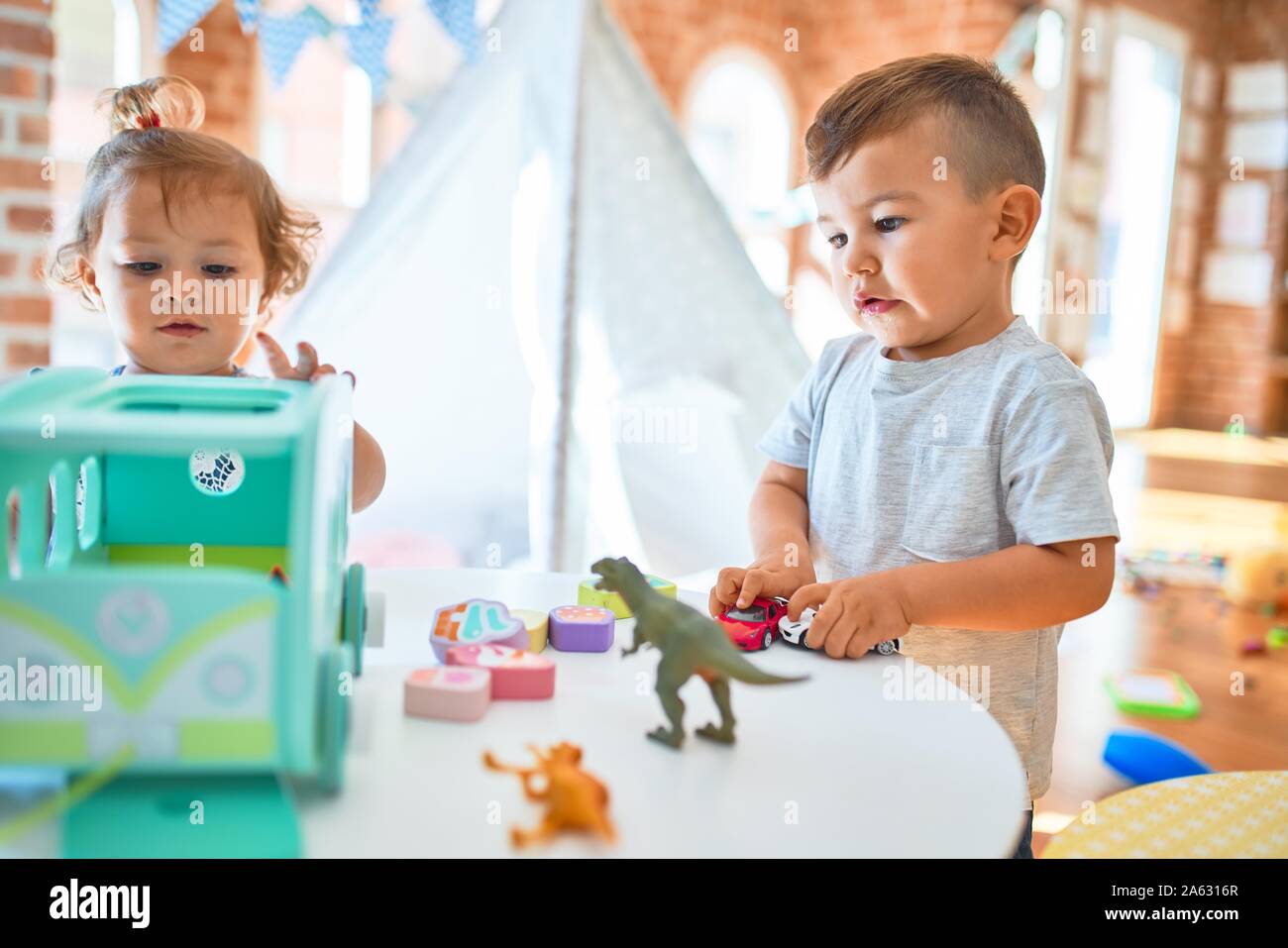 Adorable toddlers smiling happy. Standing playing around lots of toys ...