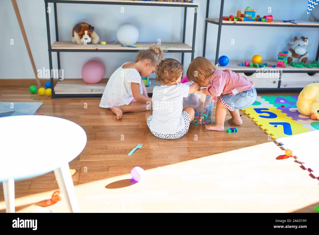Adorable toddlers playing around lots of toys at kindergarten Stock ...
