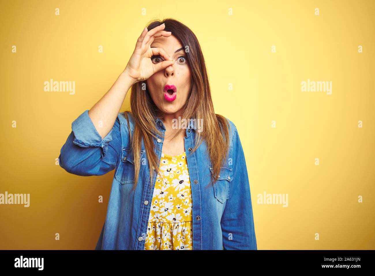 Young beautiful woman standing over yellow isolated background doing ok ...