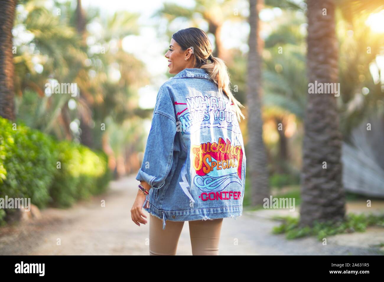 Young beautiful woman wearing denim jacket standing backwards at the ...