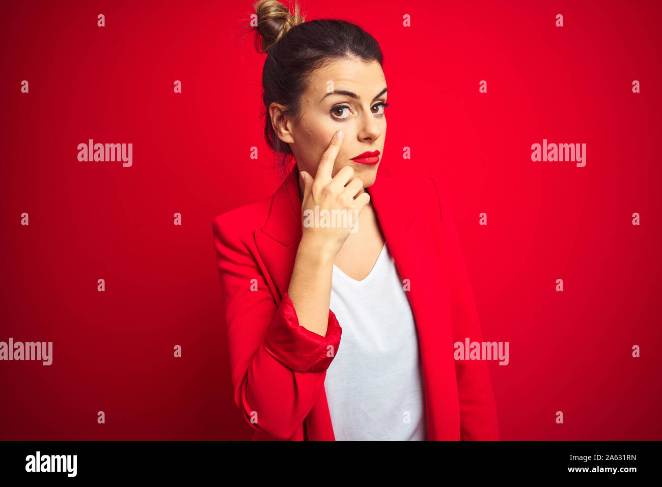 Young beautiful business woman standing over red isolated background ...