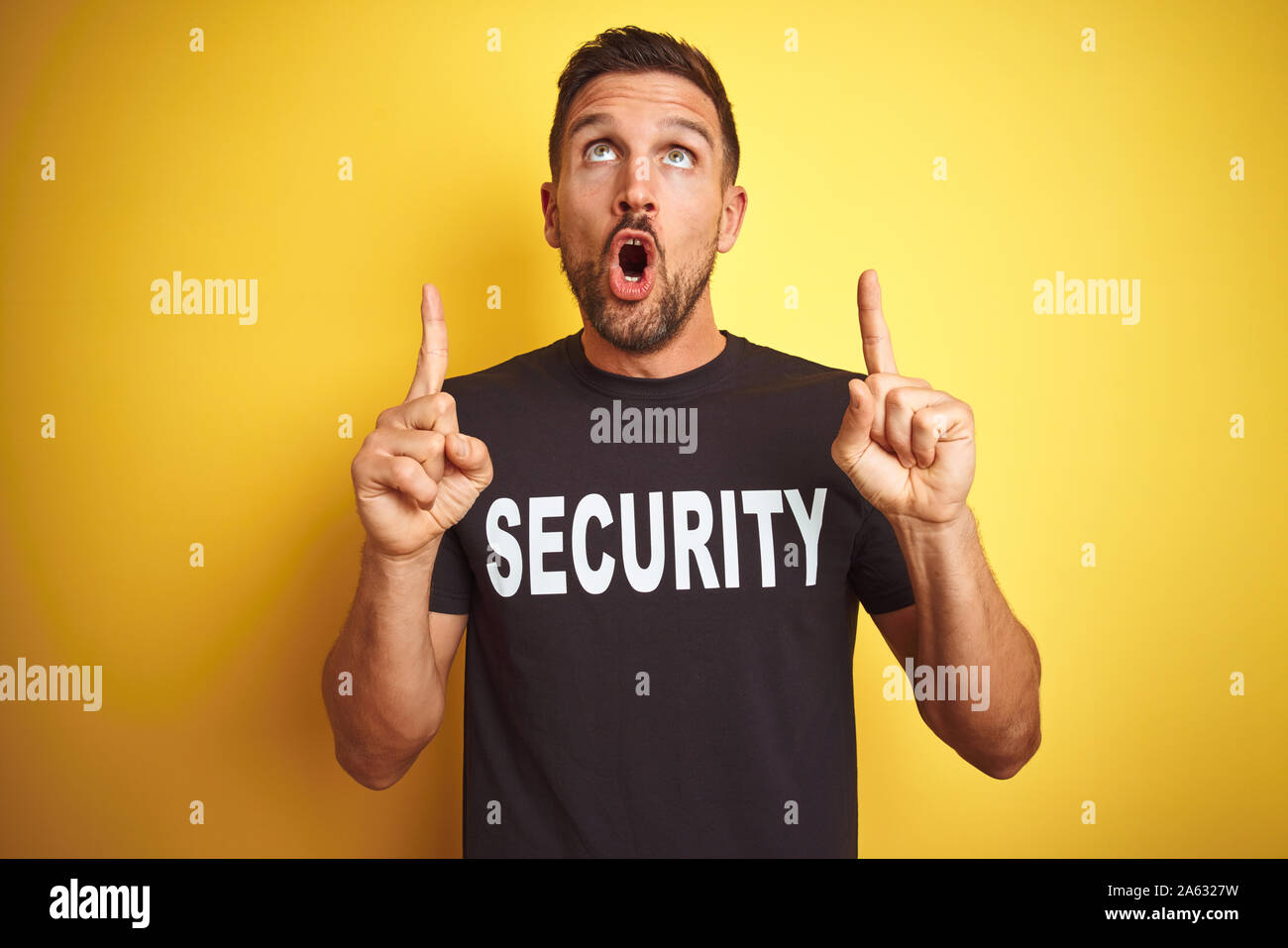 Young safeguard man wearing security uniform over yellow isolated ...