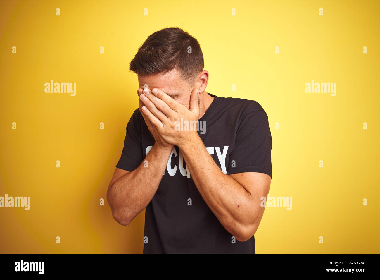 Young safeguard man wearing security uniform over yellow isolated ...