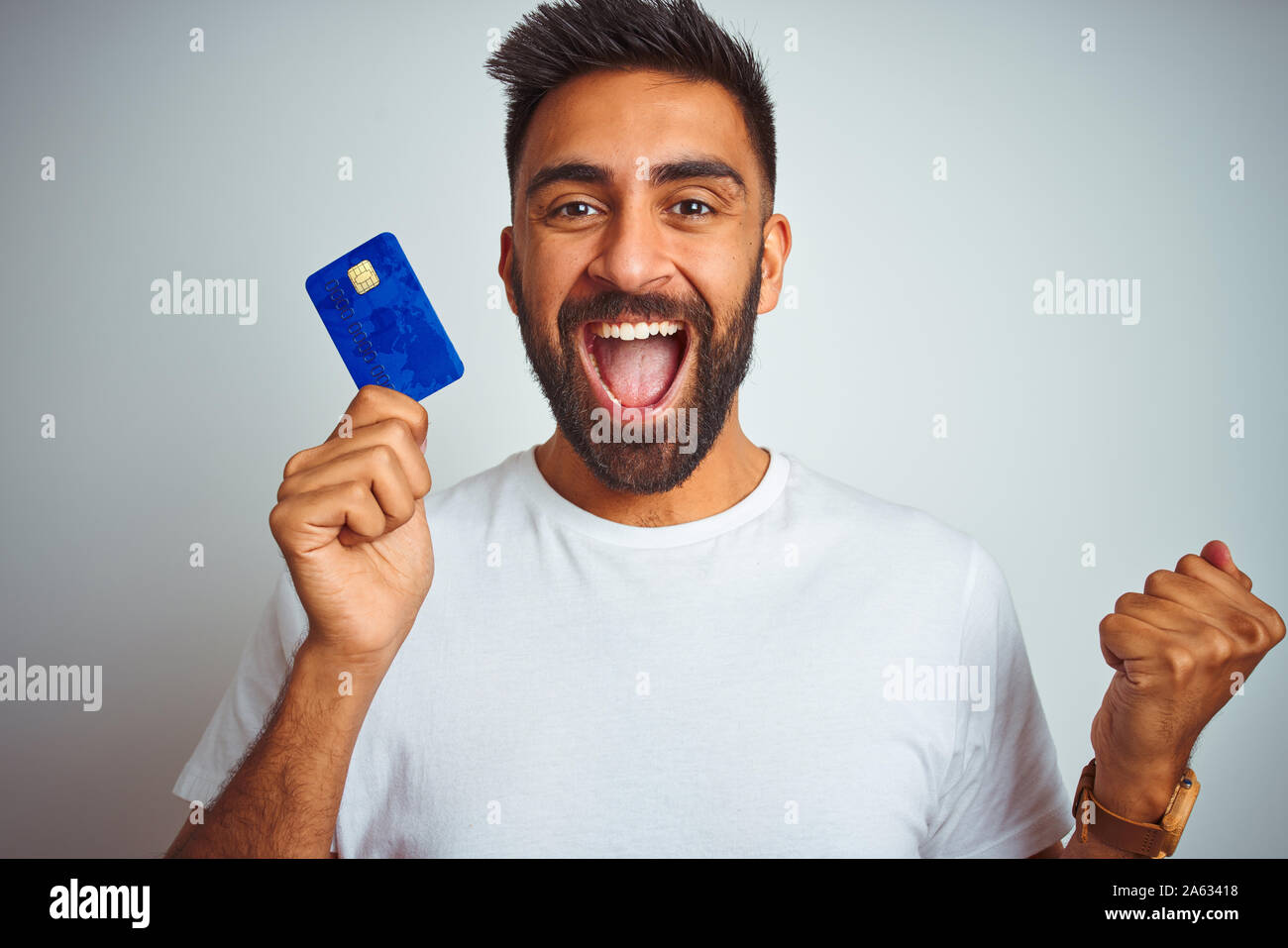 Young indian customer man holding credit card standing over isolated ...