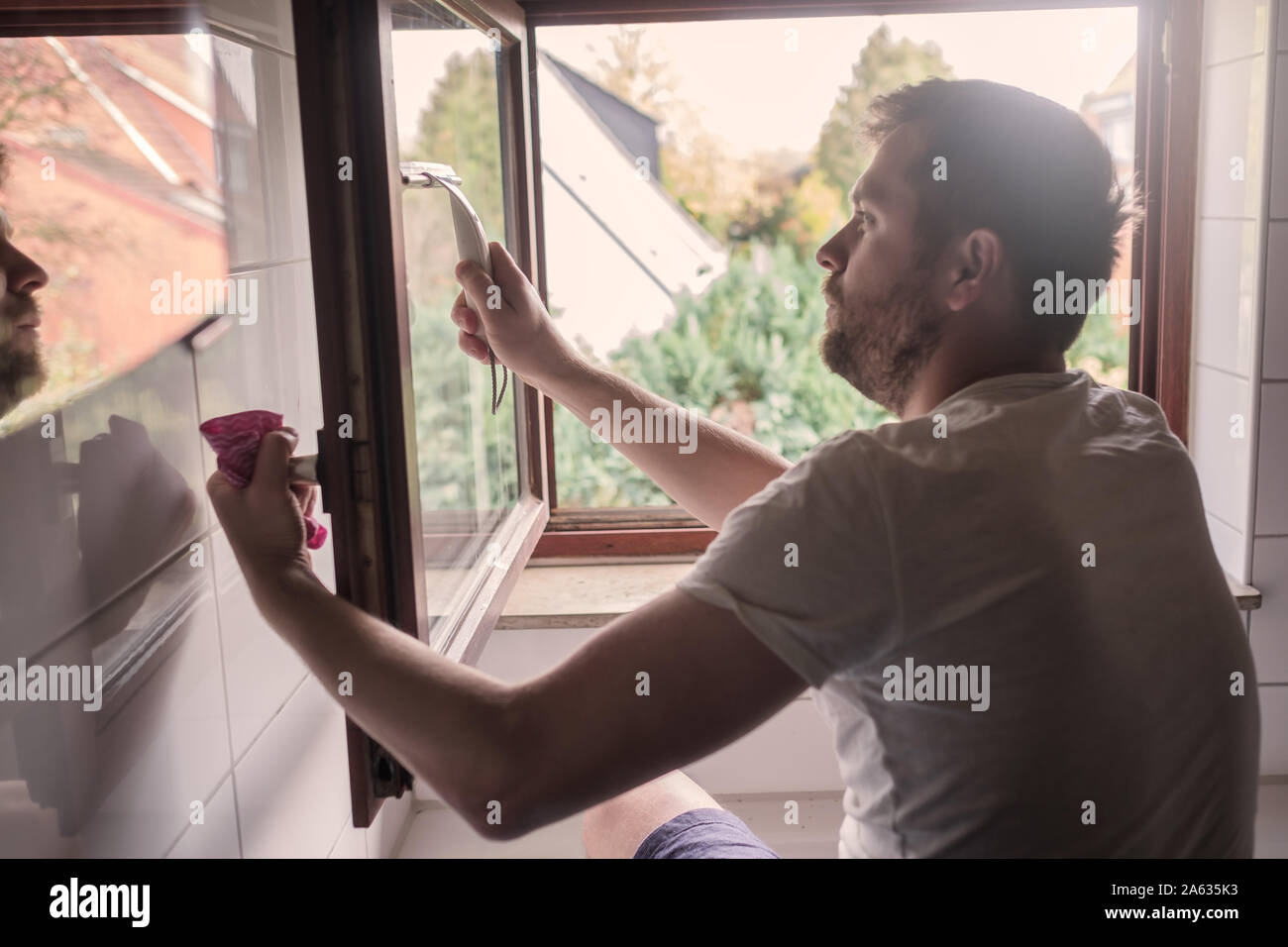 man washes a window in a house using scraper Stock Photo - Alamy