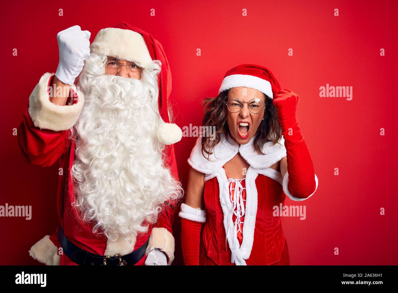 Middle age couple wearing Santa costume and glasses over isolated red ...