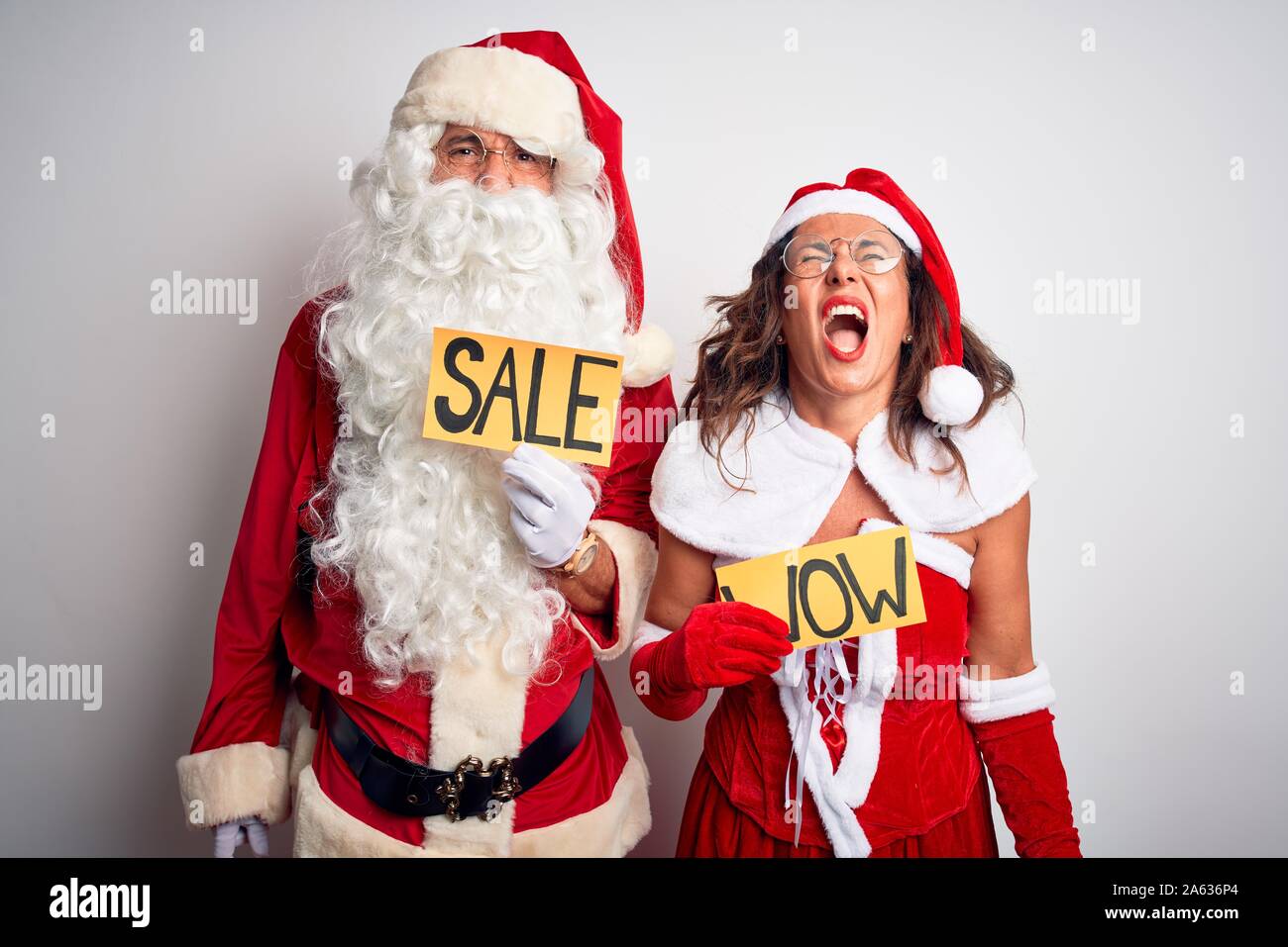 Couple wearing Santa costume holding wow and sale banner over isolated ...