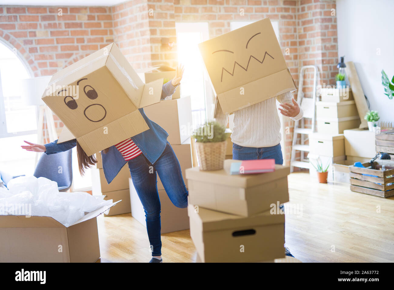 Crazy couple wearing boxes with funny faces over head, having fun happy ...