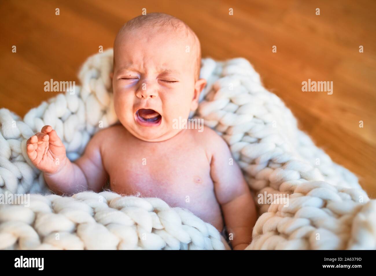 Adorable baby lying down on the floor over blanket at home. Newborn crying Stock Photo - Alamy