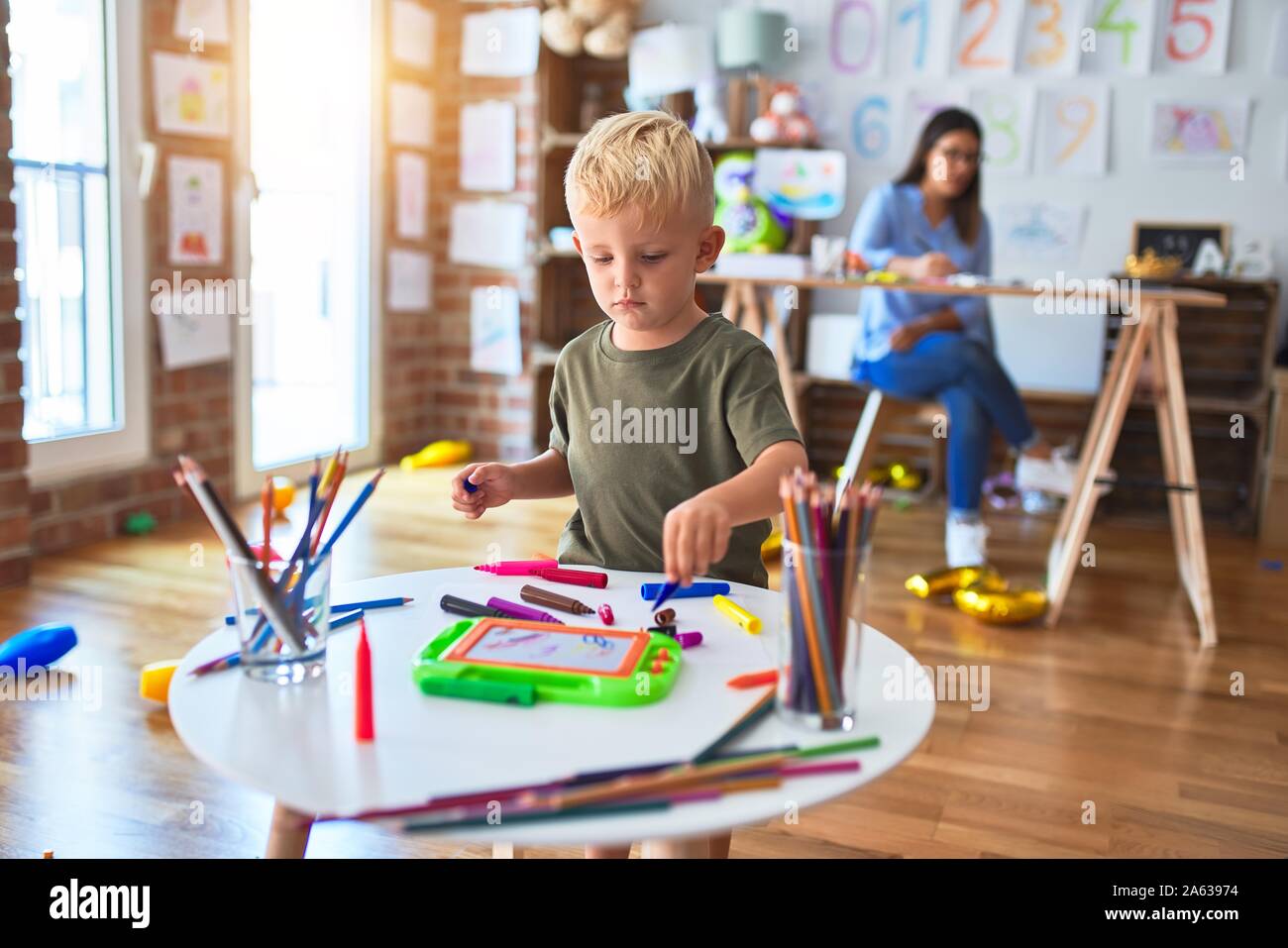 Young caucasian child playing at playschool with teacher. Mother and ...