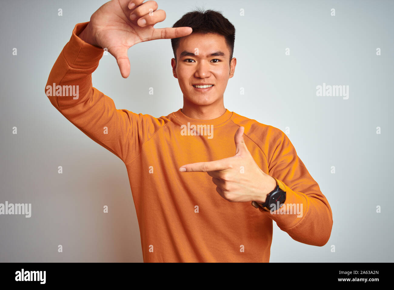 Young asian chinese man wearing orange sweater standing over isolated ...