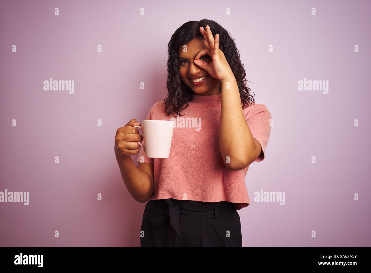 Transsexual transgender woman drinking cup of coffee over isolated pink ...
