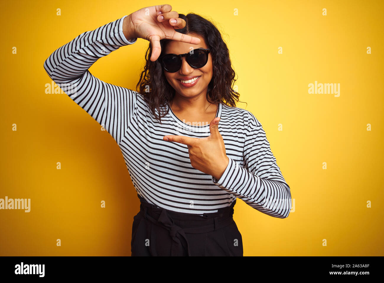 Transsexual transgender woman wearing sunglasses over isolated yellow ...