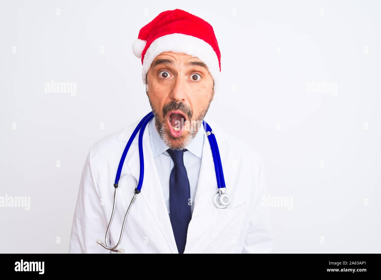 Middle age doctor man wearing christmas hat and stethoscope over ...