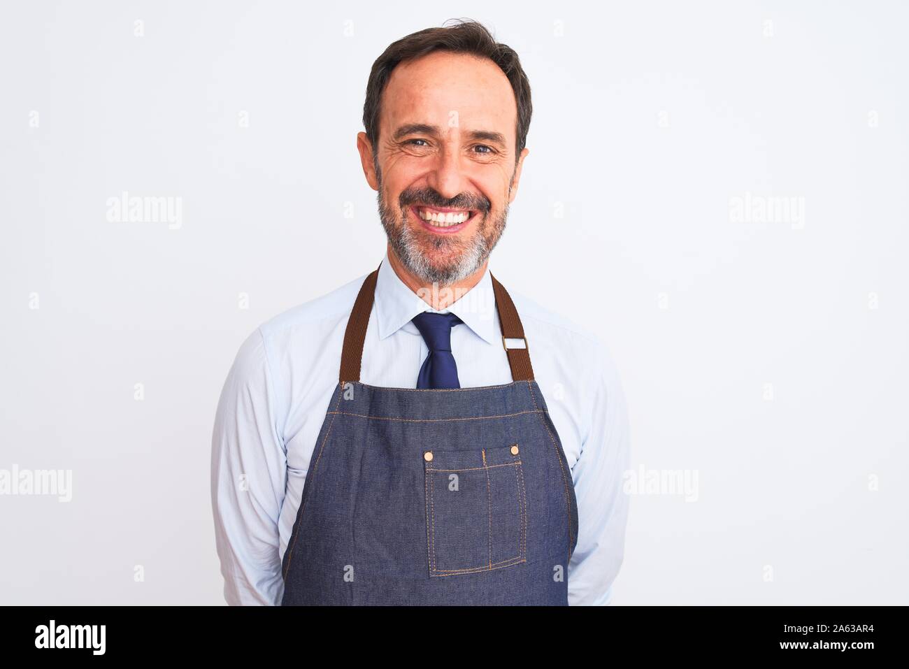 Middle age shopkeeper man wearing apron standing over isolated white ...