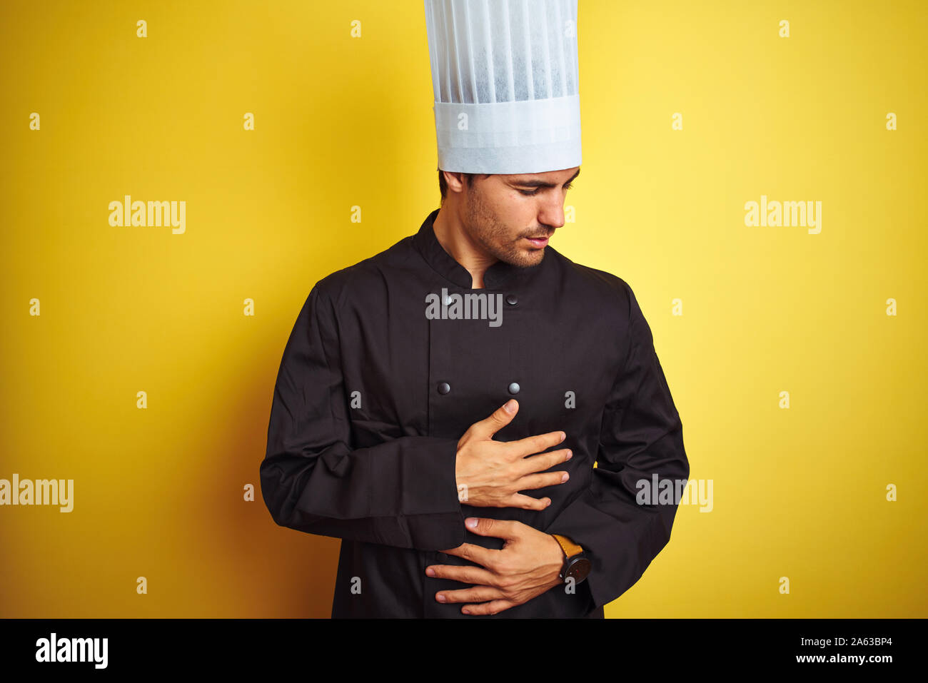 Young chef man wearing uniform and hat standing over isolated yellow ...