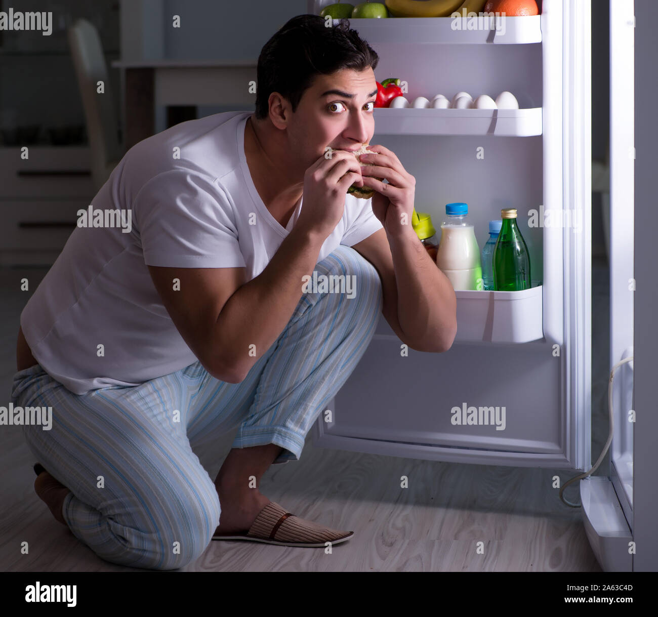 The man at the fridge eating at night Stock Photo - Alamy