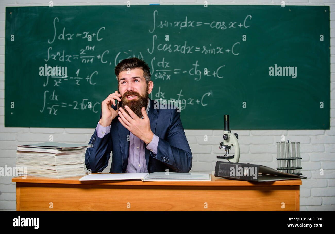 Calling parents. School teacher call mobile phone while sit classroom ...