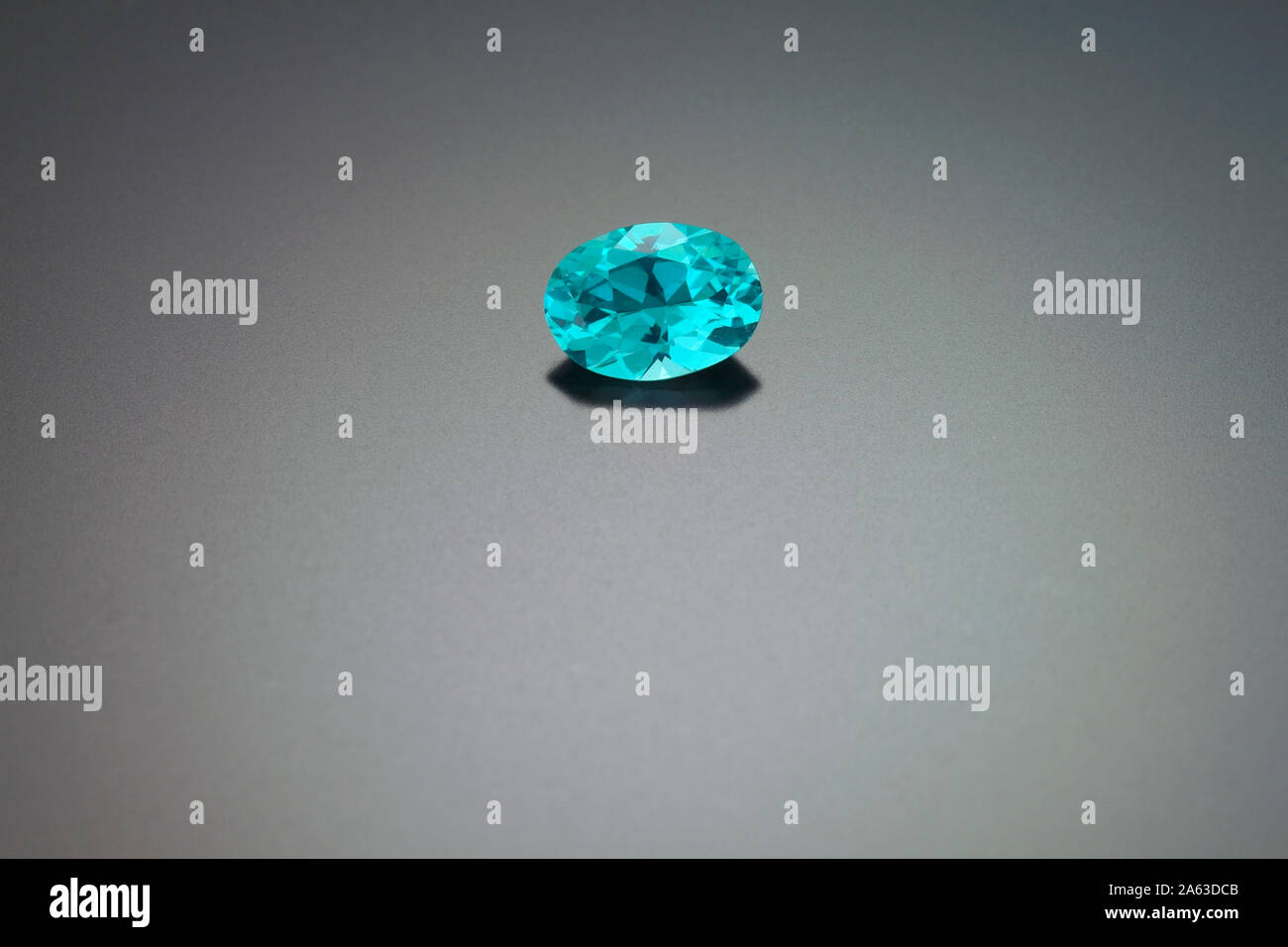 A single oval cut apatite gemstones is shown a grey reflective ...