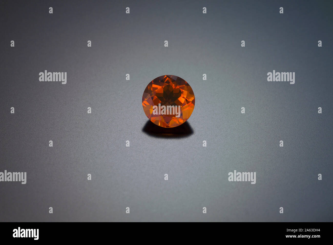 A single round cut citrine gemstones is shown a grey reflective ...