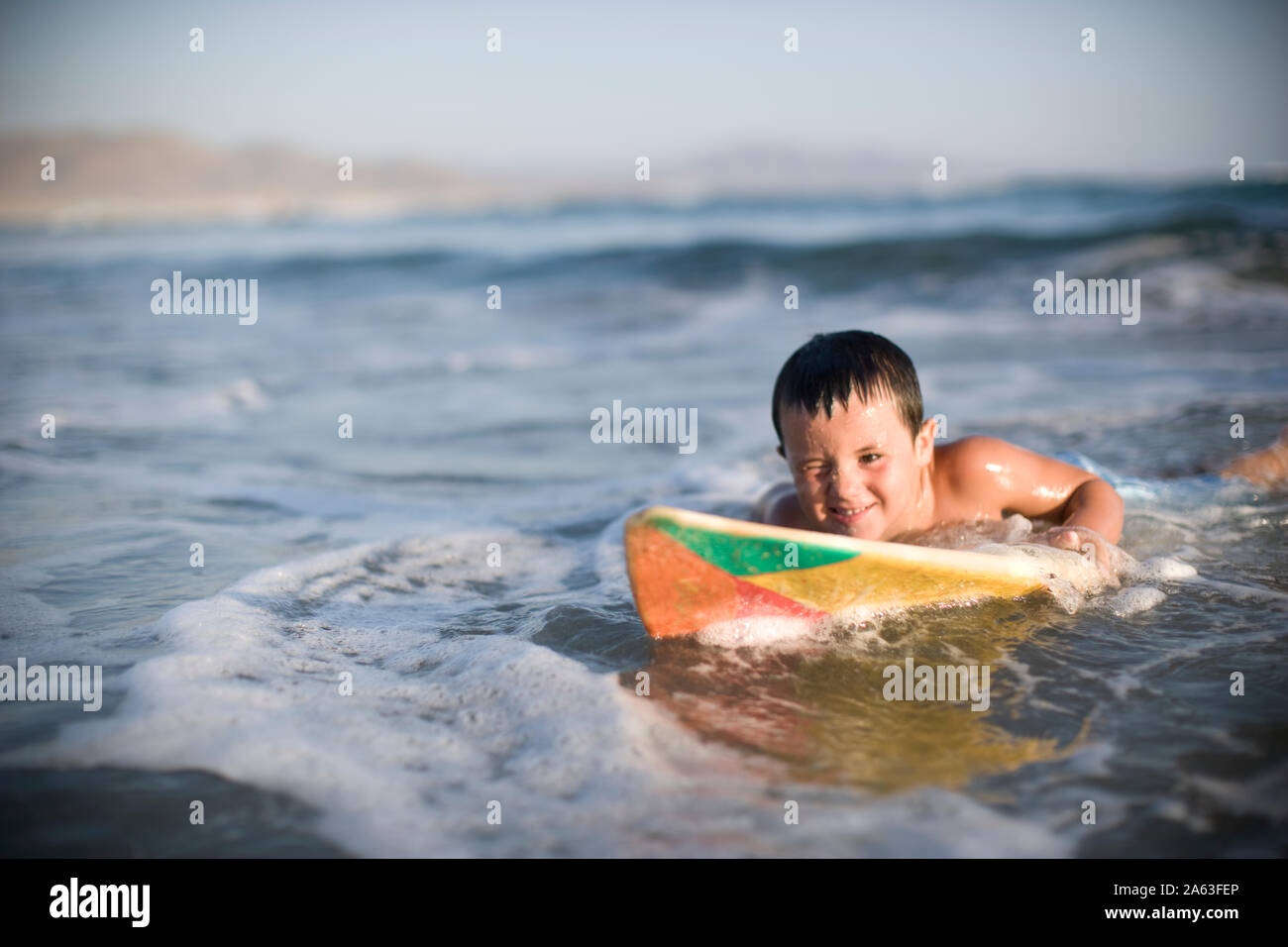 Young boy lying on a surfboard in the ocean Stock Photo - Alamy