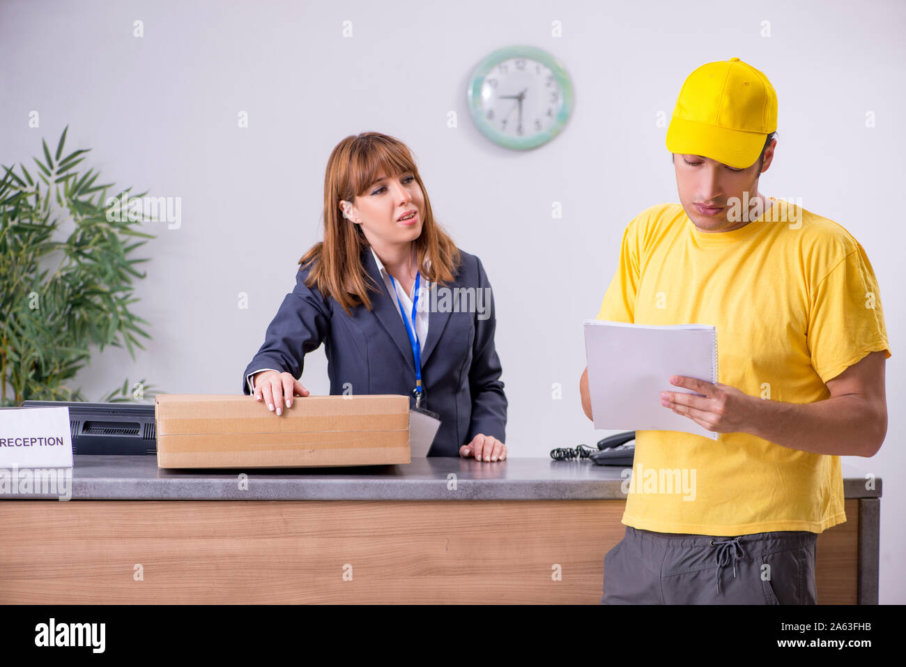 The young male courier delivering box to hotel's reception Stock Photo ...