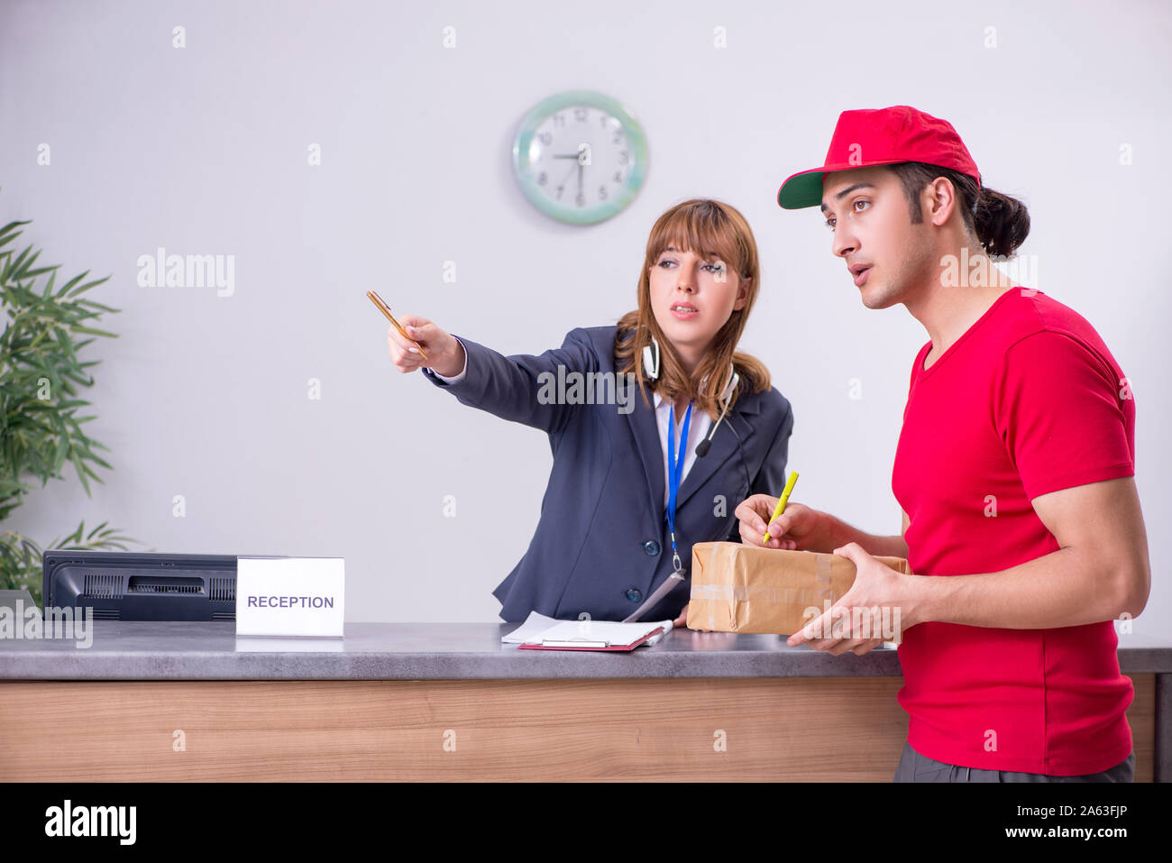 The young male courier delivering box to hotel's reception Stock Photo ...
