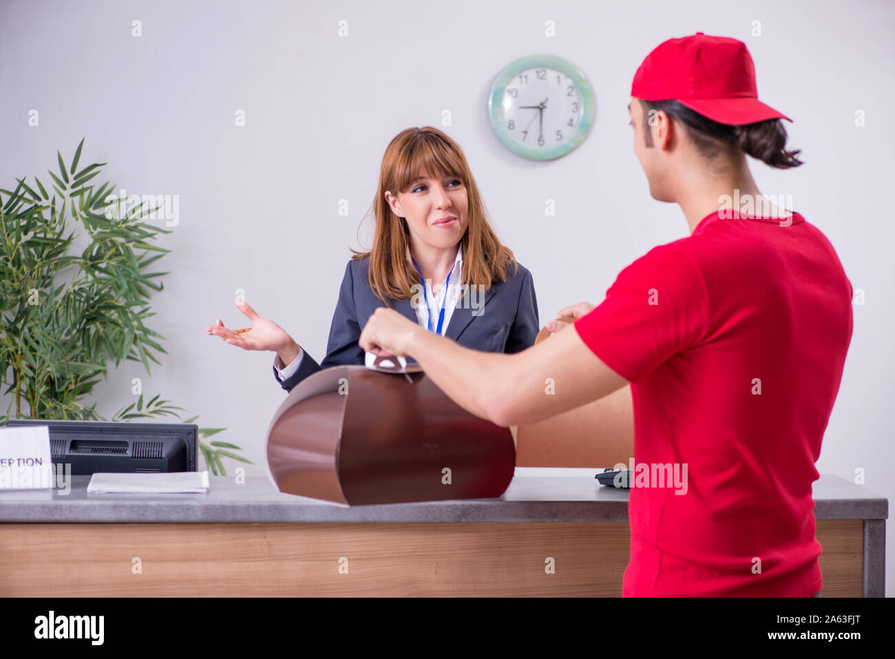 The young male courier delivering cake to hotel's reception Stock Photo ...