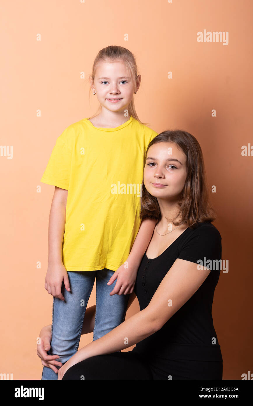 Two girls, sisters, on a light orange background Stock Photo - Alamy
