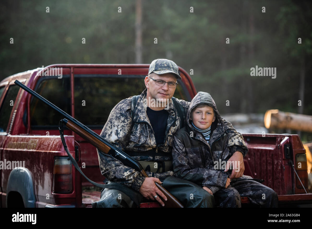 Father and son sitting in a pickup truck after hunting in forest. Dad ...