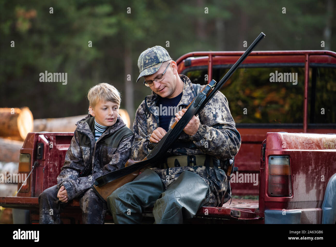 Father and son sitting in a pickup truck after hunting in forest. Dad ...