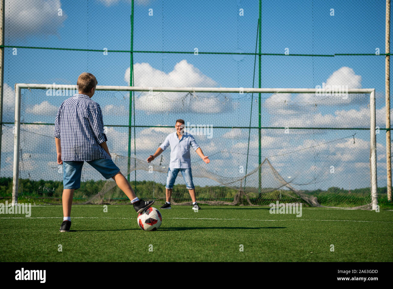 Happy father and excited son playing together soccer on a green ...