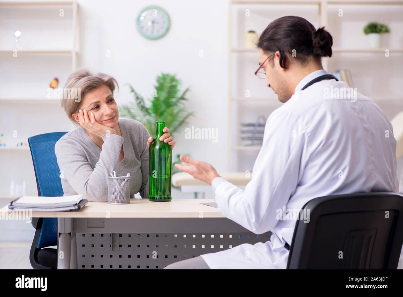 The female alcoholic visiting young male doctor Stock Photo - Alamy