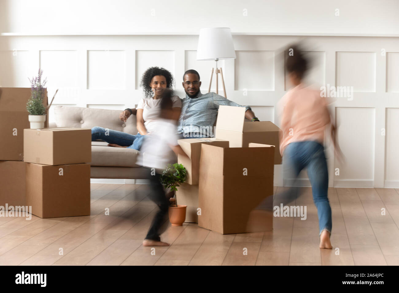 Young parents watch small kids running on moving day Stock Photo - Alamy