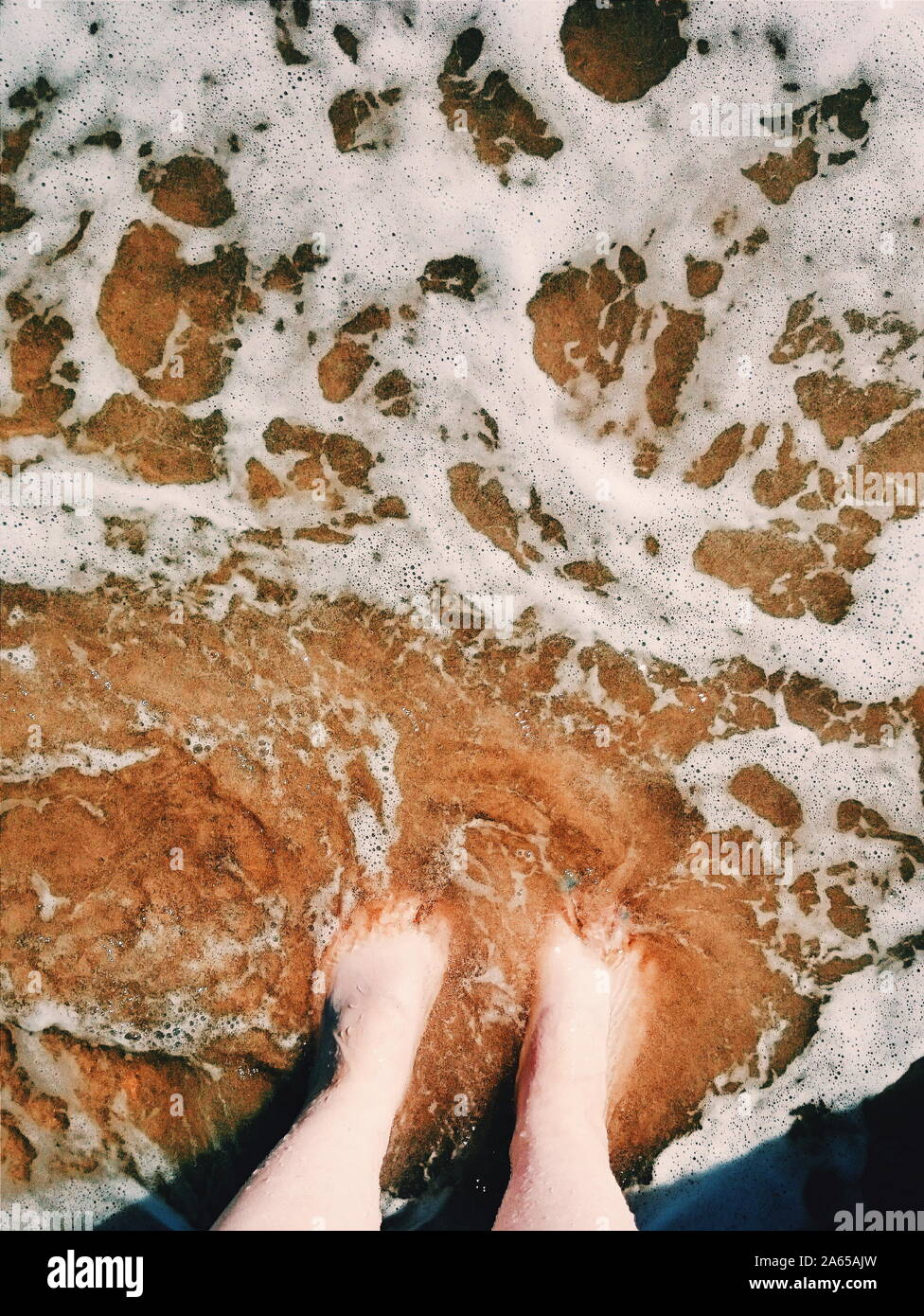 Overhead view of woman standing with her feet in the sea Stock Photo ...