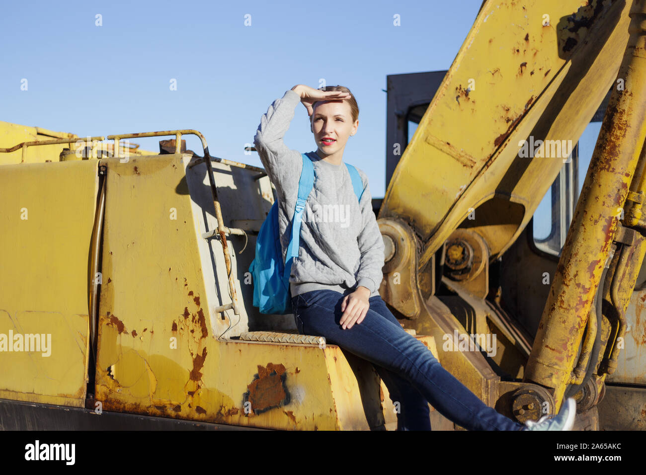 Young happy woman sitting on an yellow excavator Stock Photo - Alamy