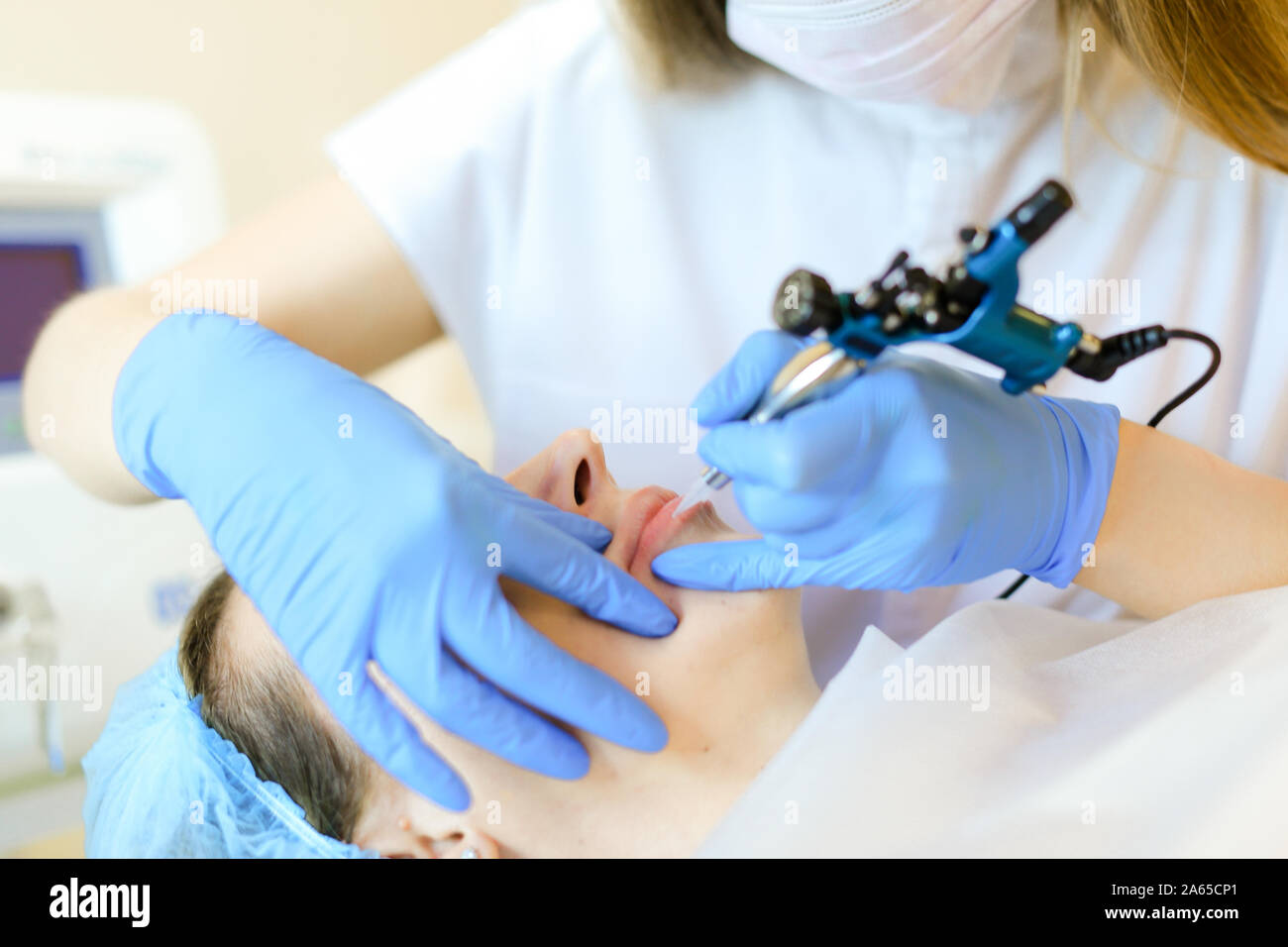 Close up hands in blue latex gloves making permanet lip tattoo with ...