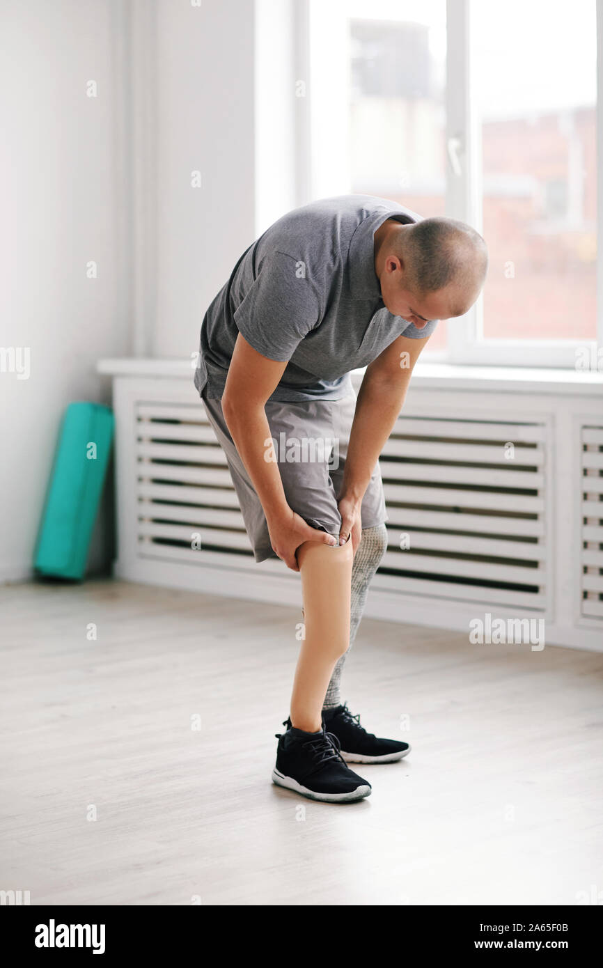 Young man standing in the room and touching his prosthesis leg Stock ...