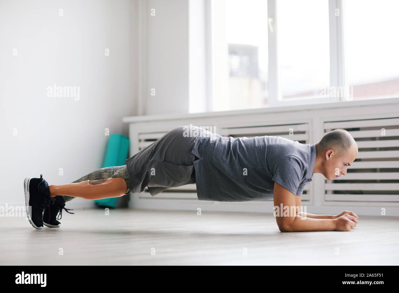 Young disabled man in sports clothing doing push-ups during sports ...