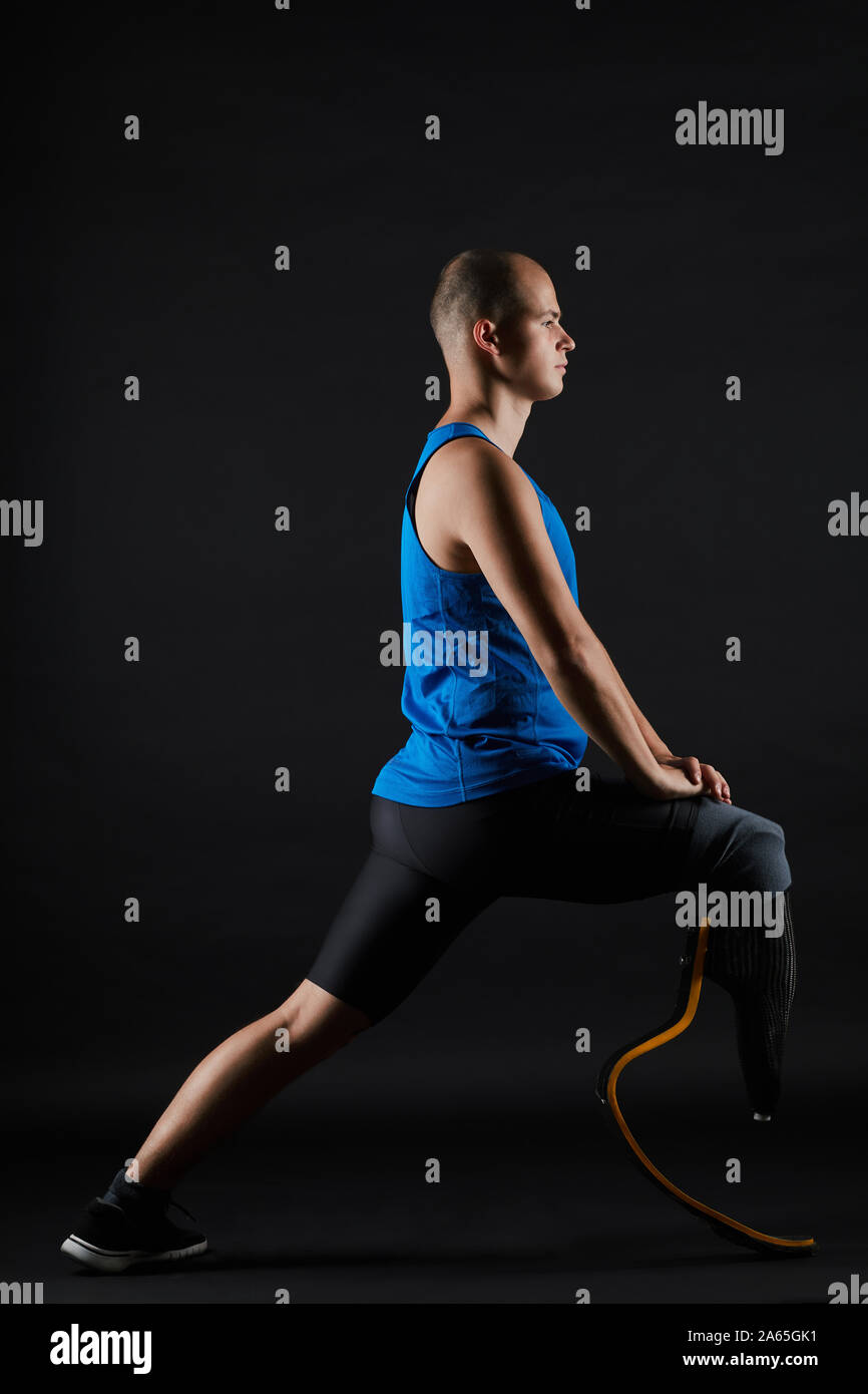 Side view of paralympic runner with prosthesis warming up before ...