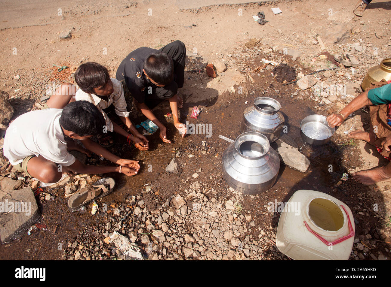 Children drinking water from puddle, Shahapur, Mumbai, Maharashtra ...