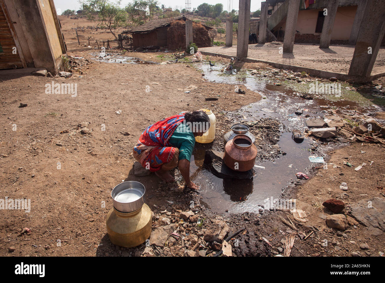 Woman collecting water from puddle, Shahapur, Mumbai, Maharashtra ...
