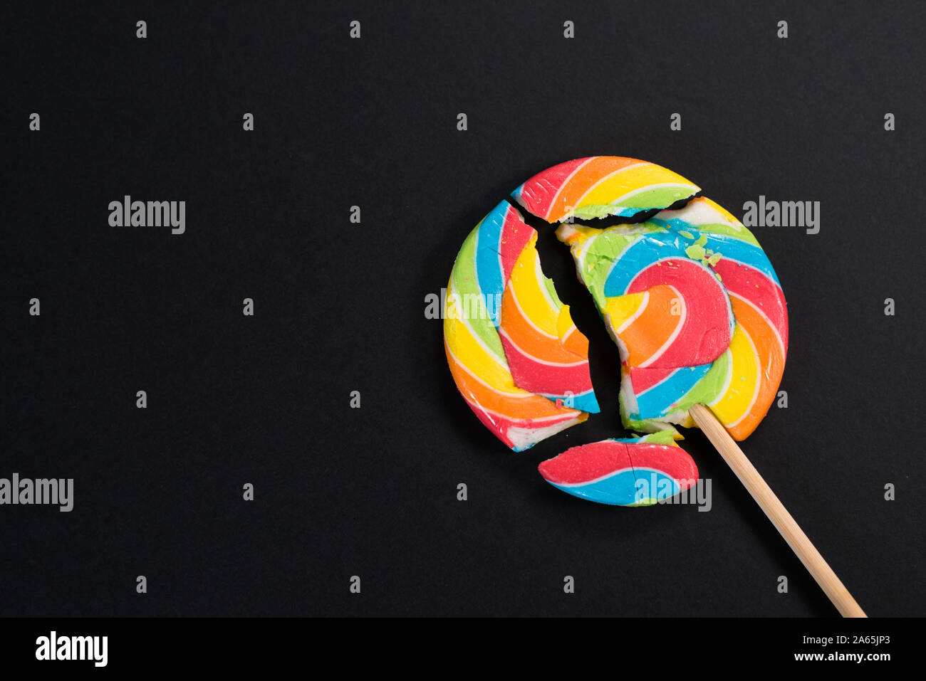 Swirl round broken lollipop on black background. concept of unhealthy ...